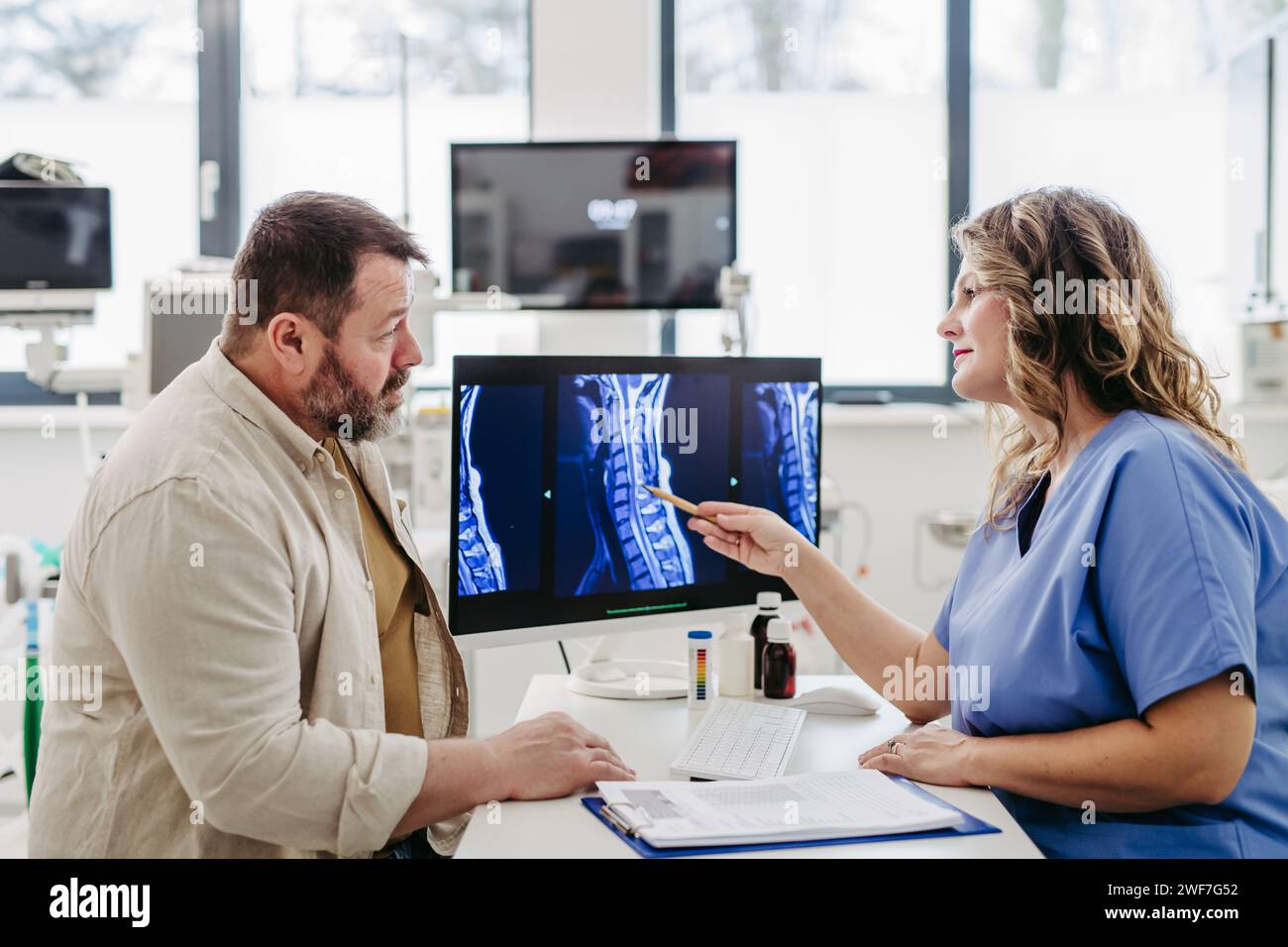 Doctor consulting with overweight patient, discussing test result and x ...