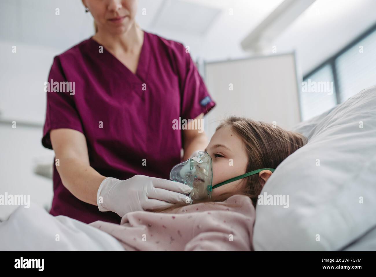 Nurse putting an oxygen mask on a girl's face. Child patient in ...