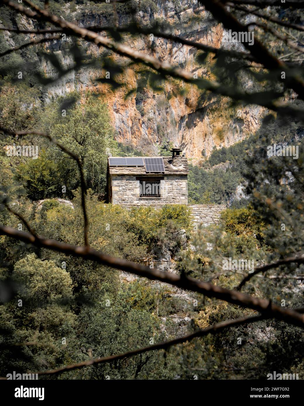 Small stone house in a mountain gorge seen through the leaves ve Stock ...