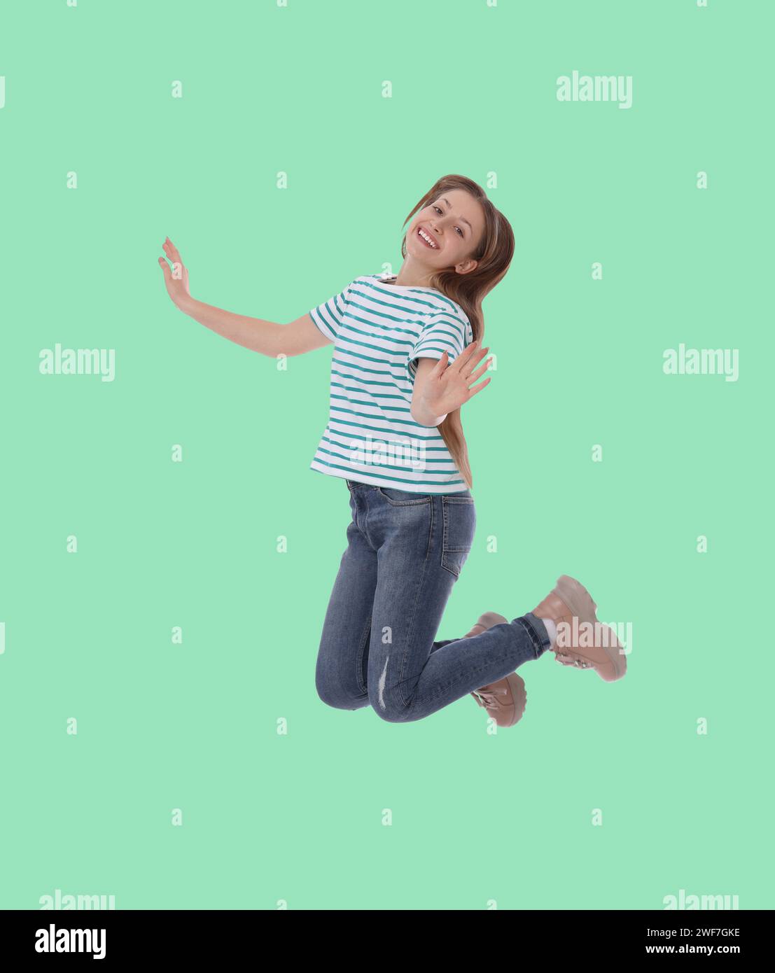 Happy cute girl jumping on light turquoise background Stock Photo - Alamy