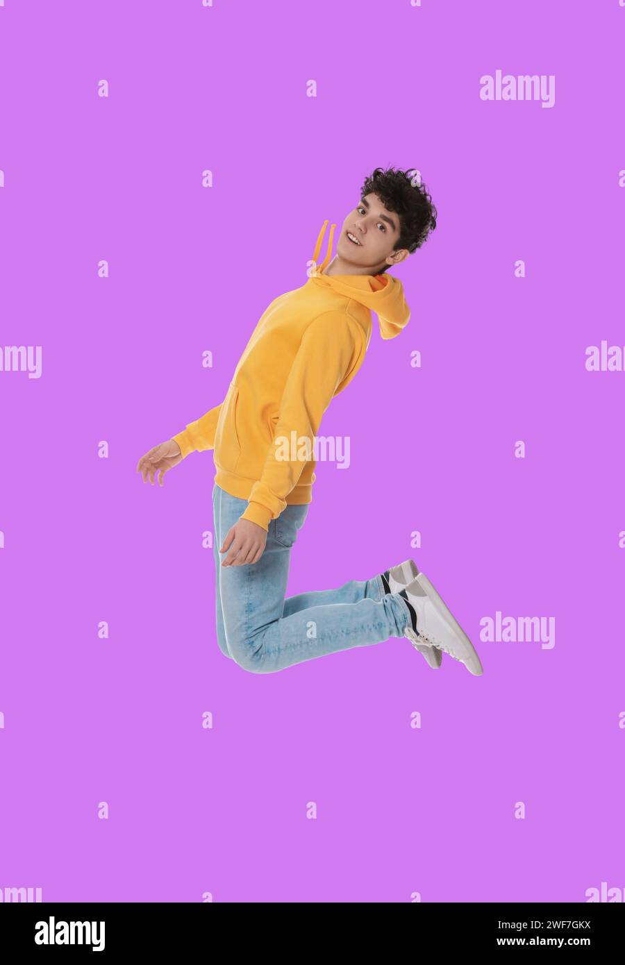 Teenage boy jumping on violet background, full length portrait Stock ...