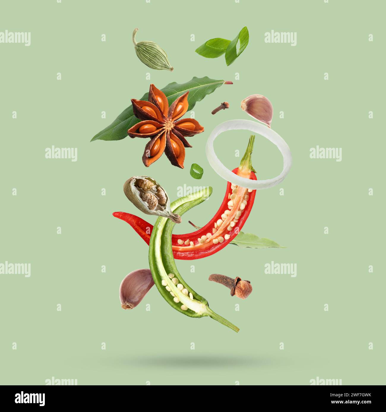 Different spices falling on light green background Stock Photo - Alamy