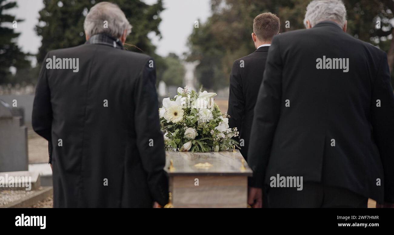 Men, coffin and pallbearers walking at cemetery ceremony outdoor at ...