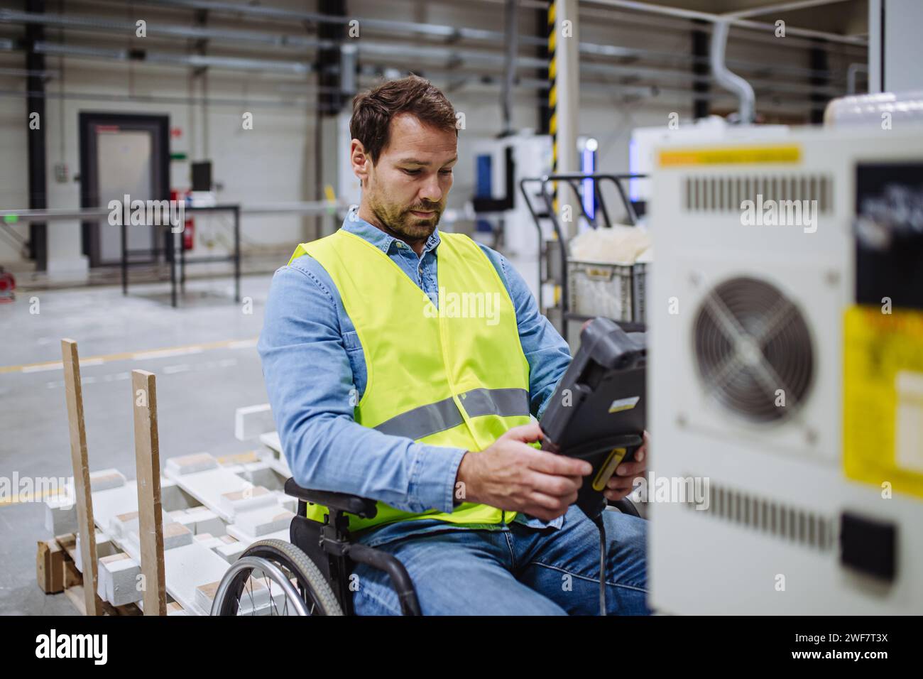 Portrait of man in wheelchair working in modern industrial factory ...