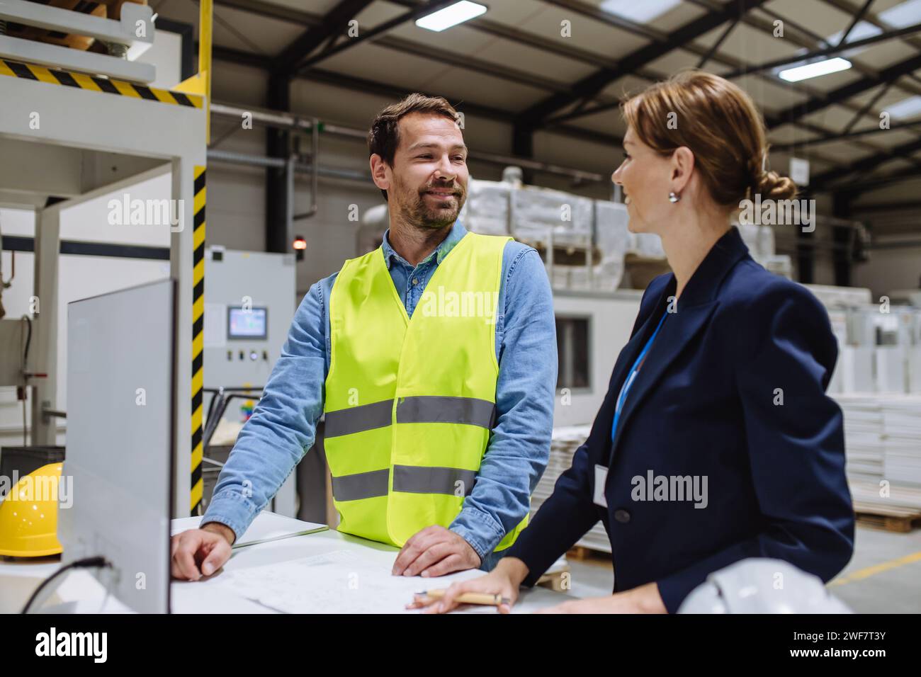 Female warehouse director talking with production manager, discussing ...