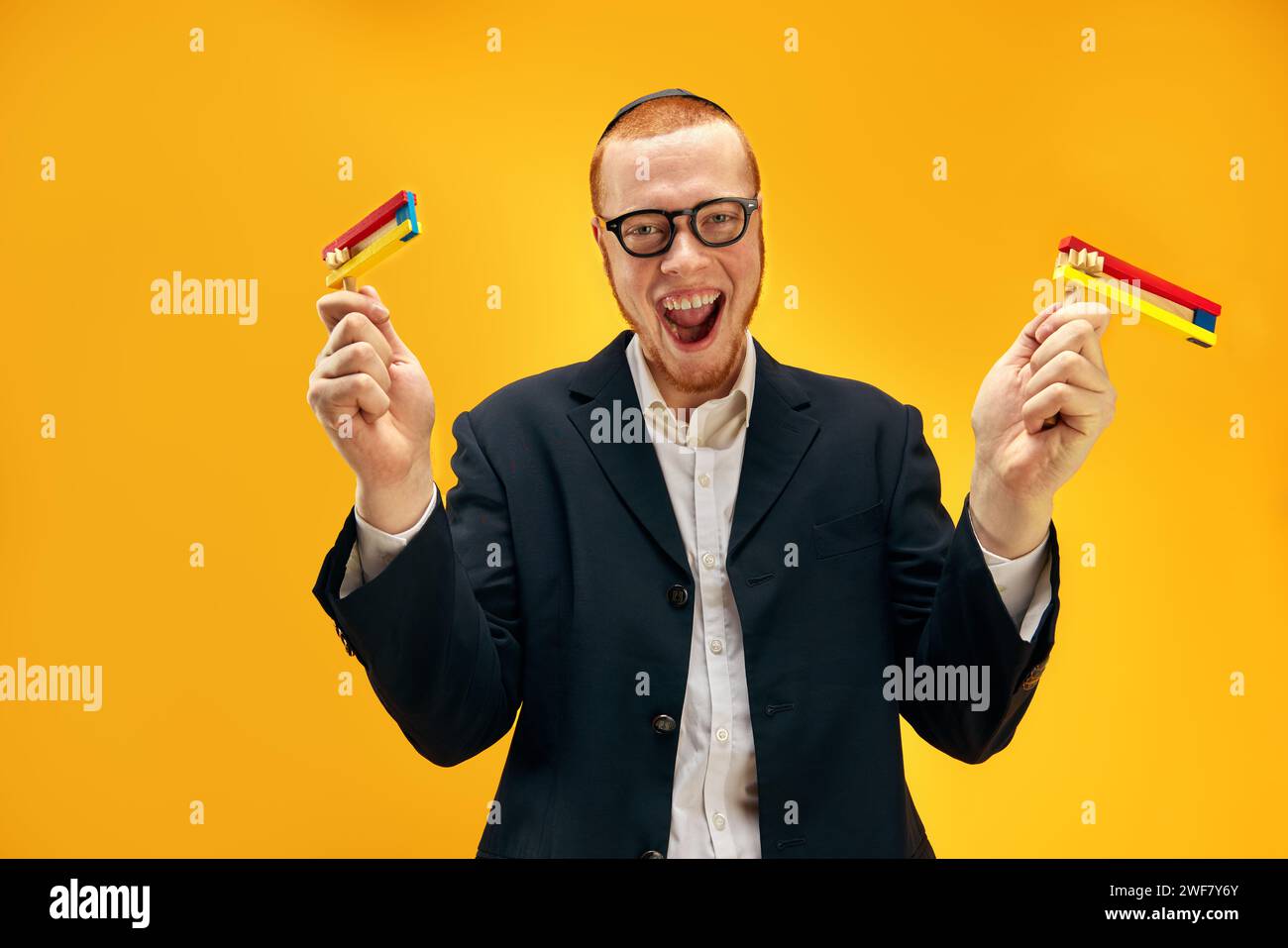 Young redhead Jewish man in glasses, yarmulke playing with wooden ...