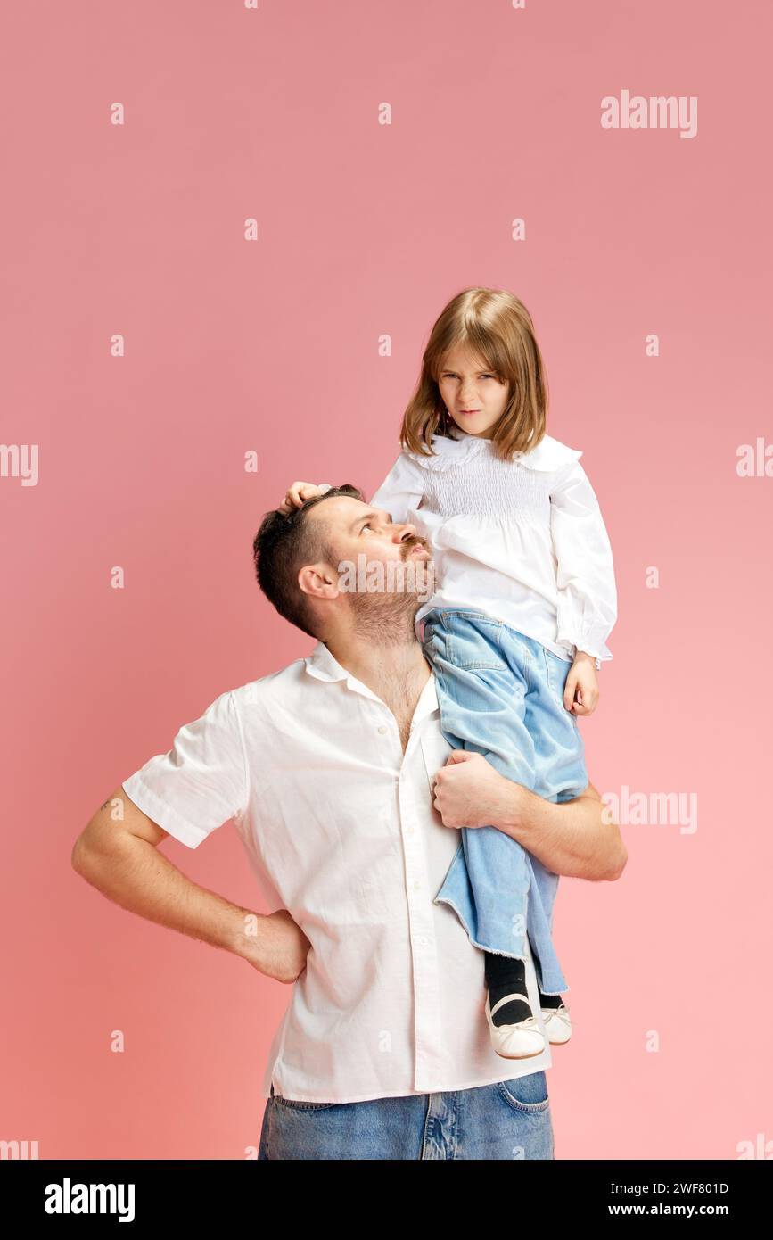 Man with serious expression carrying a child on hip, child looking down ...