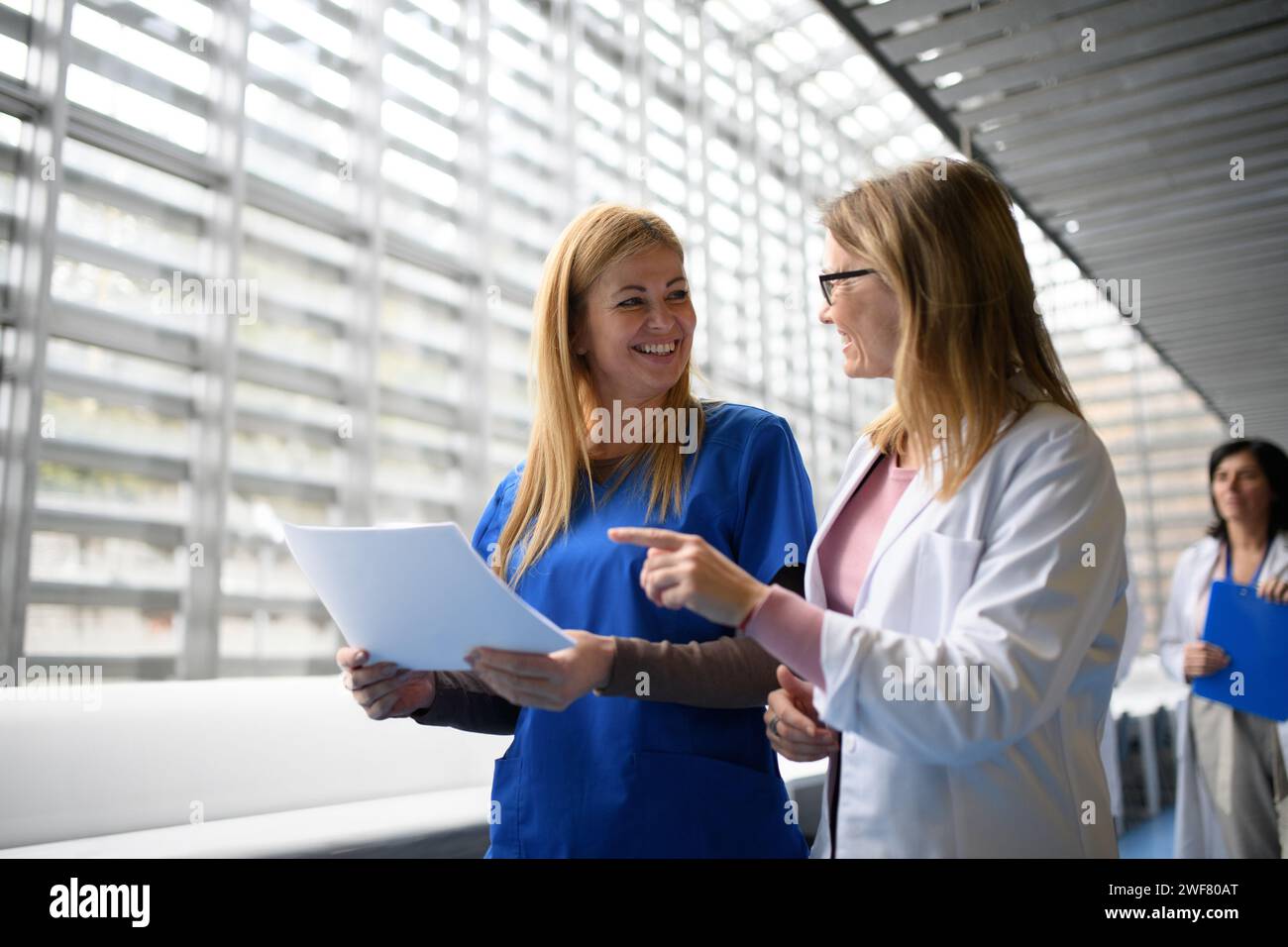 Two female doctors discussing test results, patients diagnosis. walking ...