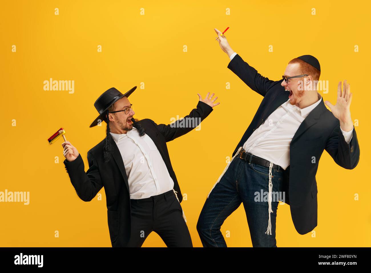 Two emotional Jewish man, friends in suits, yarmulke, with noisemaker ...