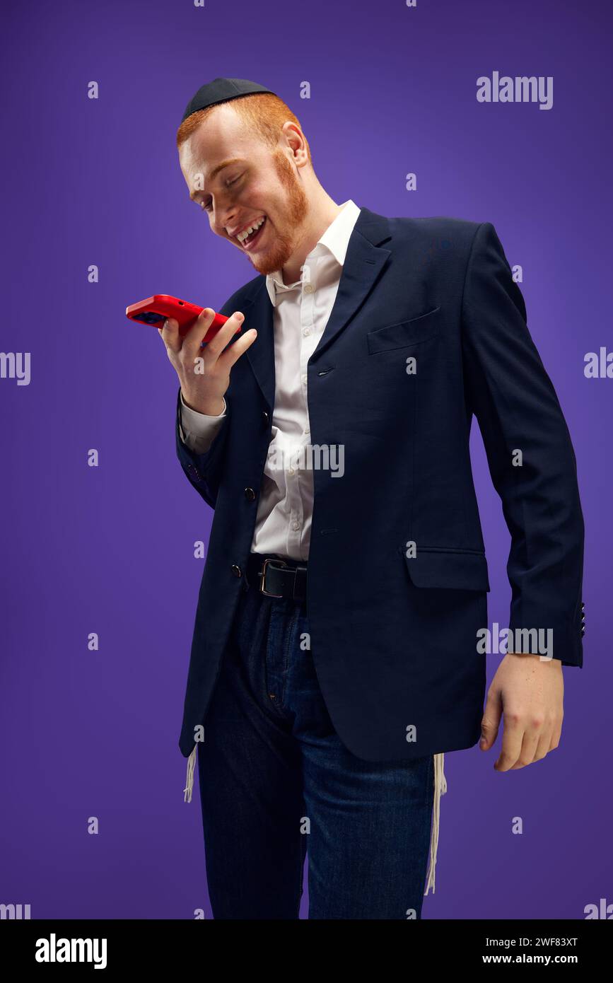 Young smiling redhead emotional Jewish man looking on phone, greeting ...