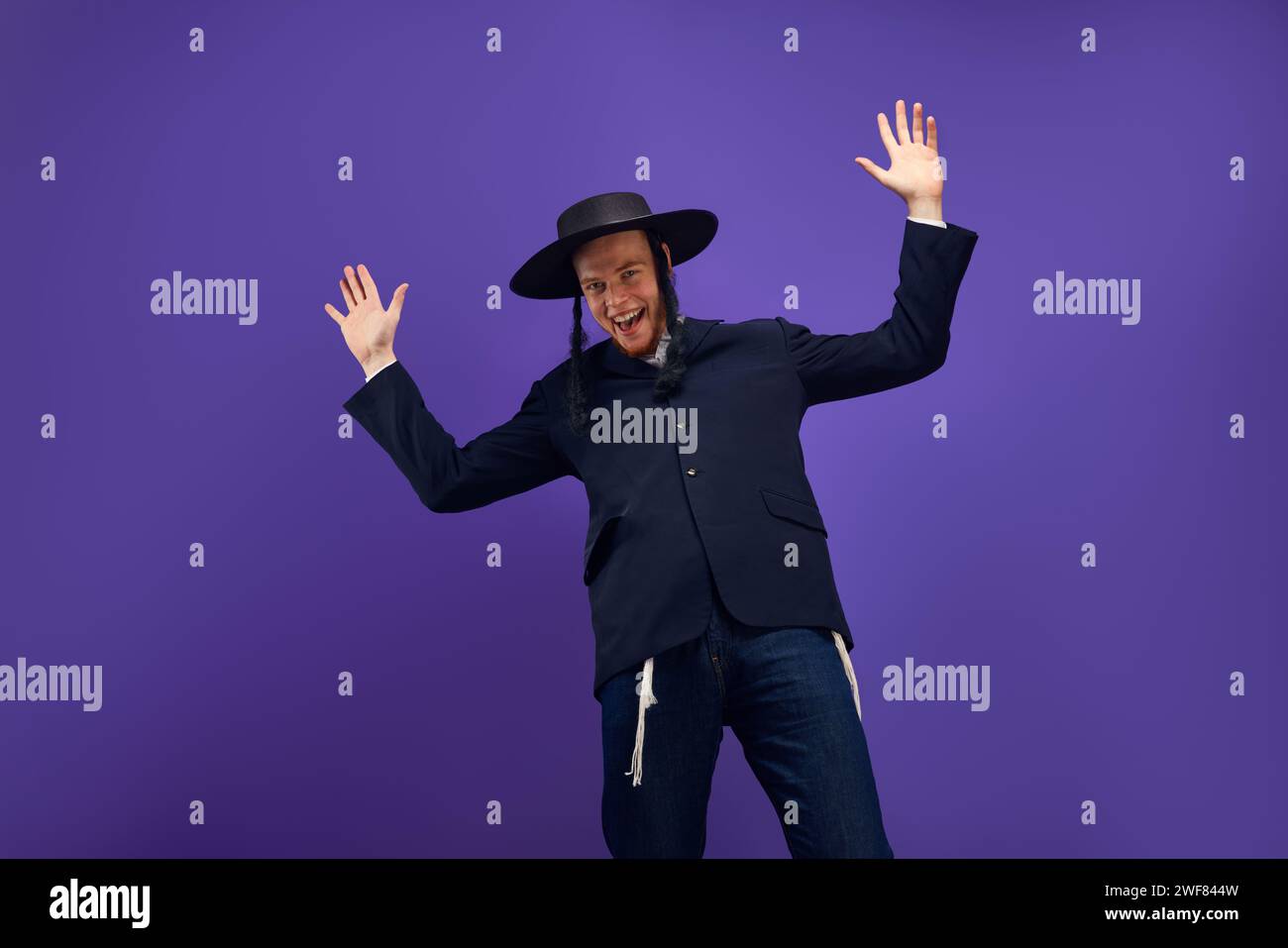 Happy and excited young Jewish man with sidelocks in hat, costume ...