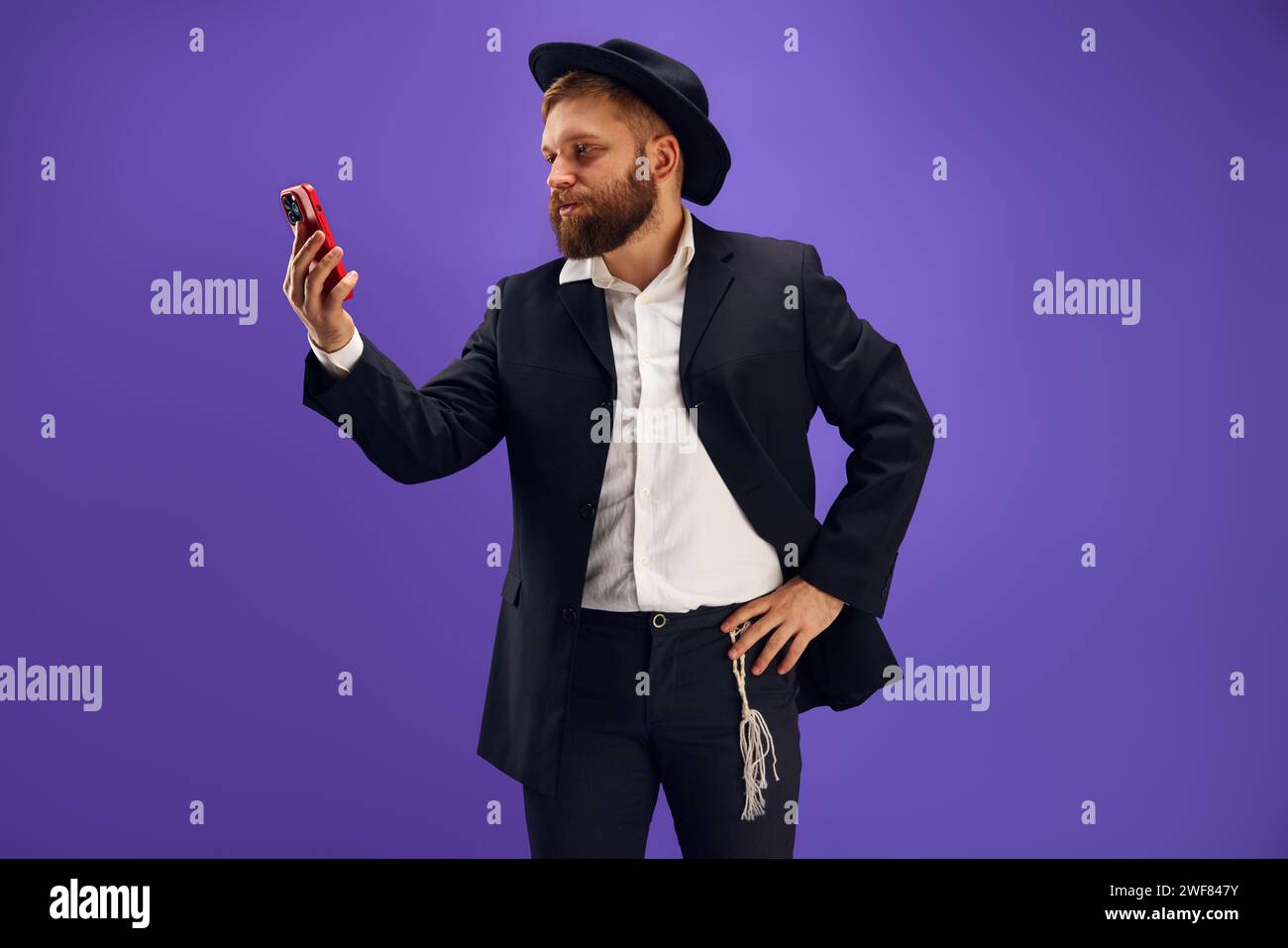 Bearded young Jewish man emotionally looking on mobile phone screen ...