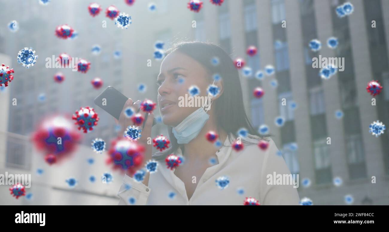 Multiple covid-19 cells floating against woman with lowered face mask ...
