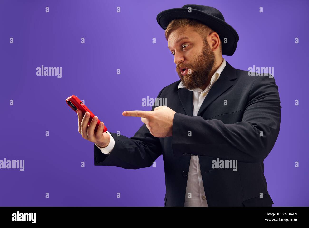 Bearded young Jewish man emotionally looking on mobile phone screen ...