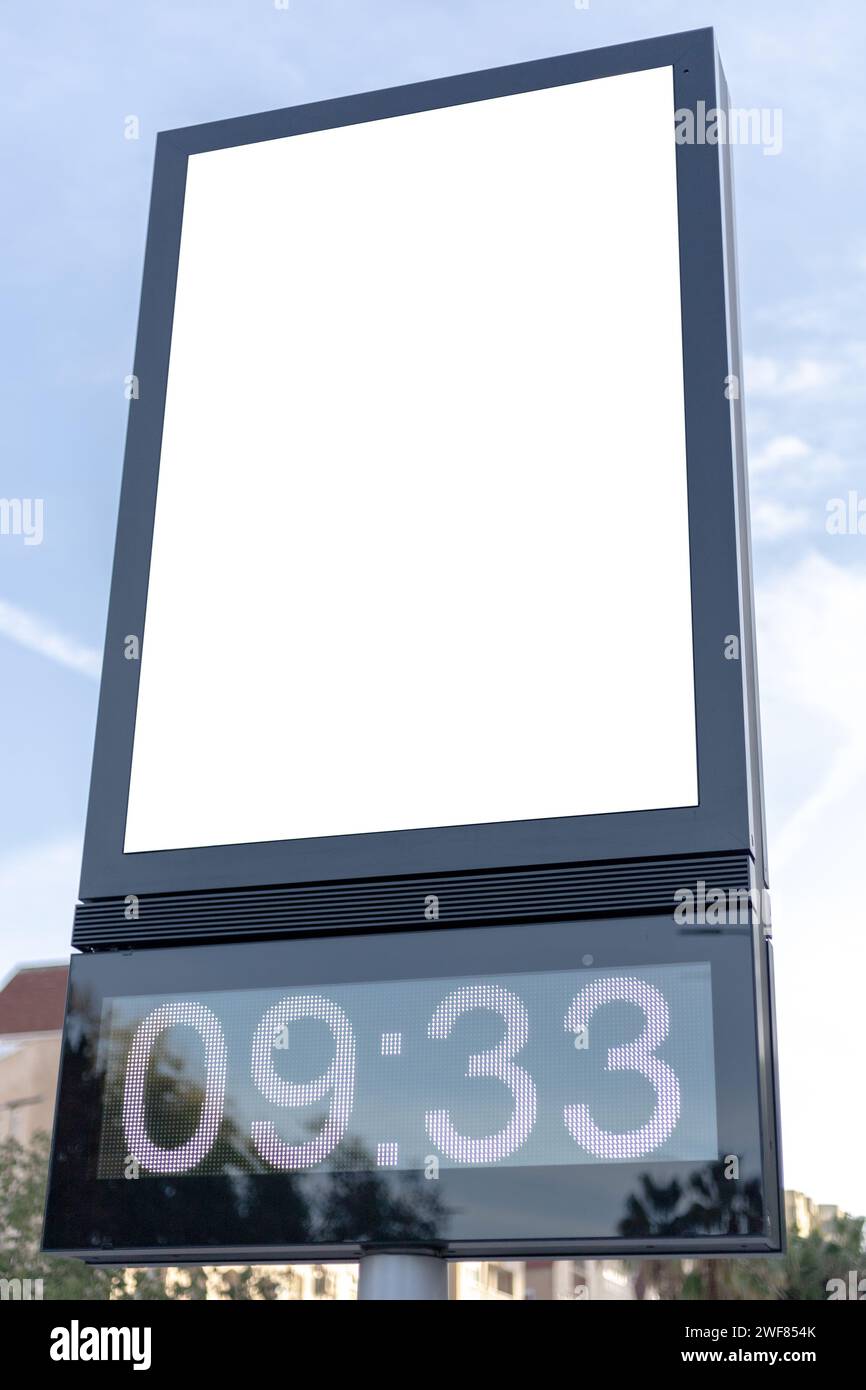 Urban digital clock post with a blank advertising panel against a ...