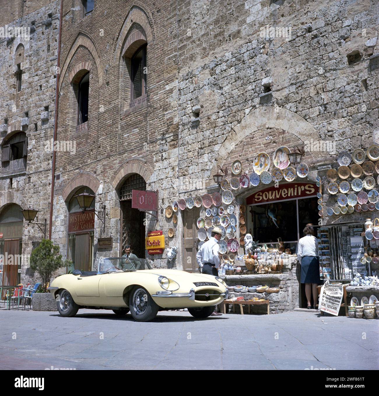 Primrose Yellow convertible Jaguar E-type parked outside souvenier shop ...