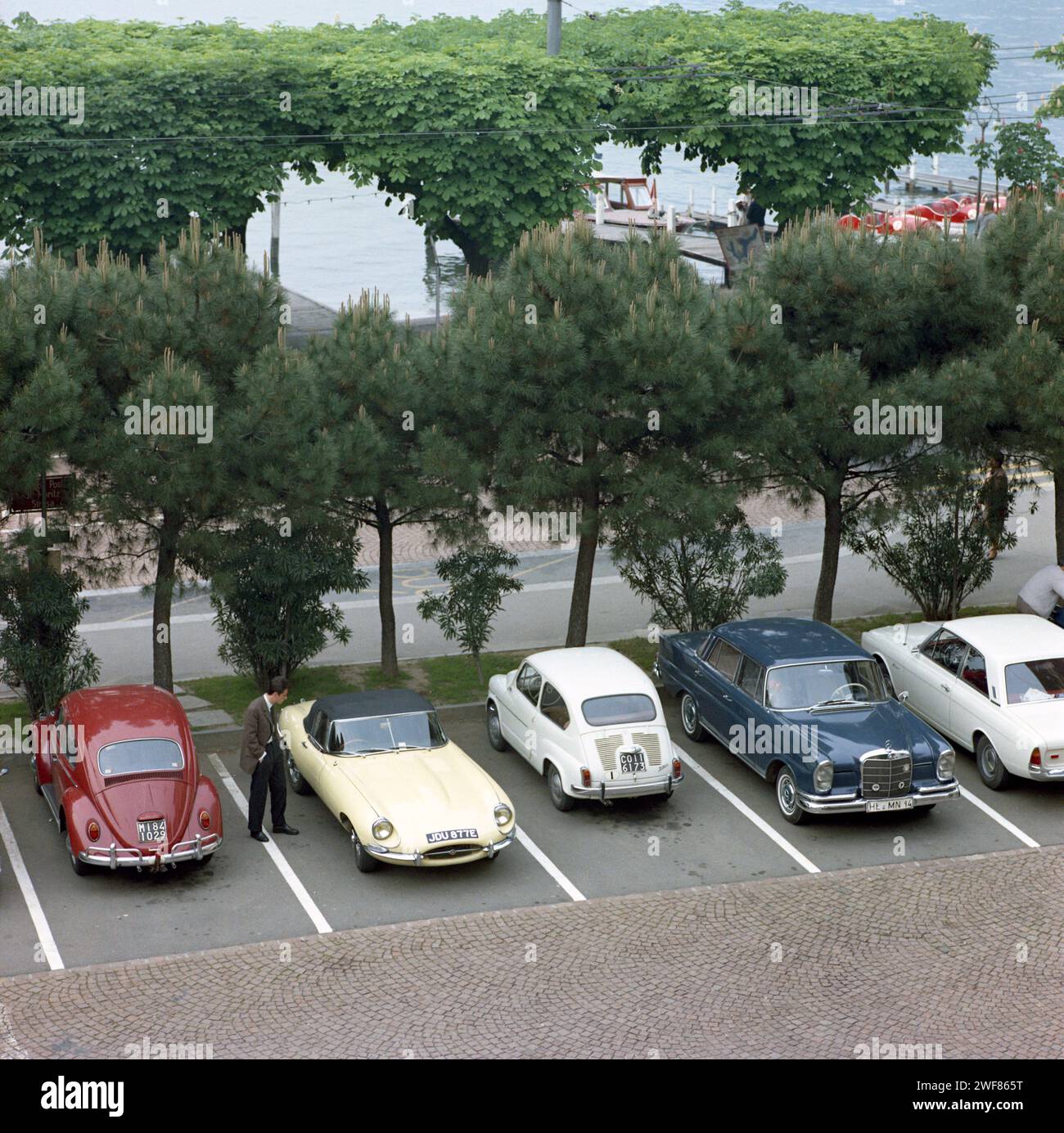 An onlooker inspects a 1967 Jaguar E-type, convertible, Pale Primrose ...