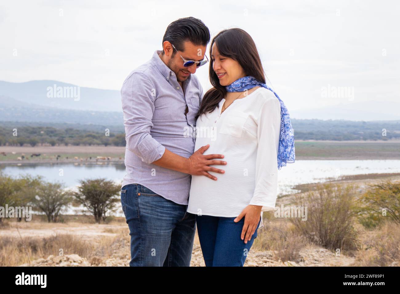 A couple embraces while standing in a natural landscape with the man ...