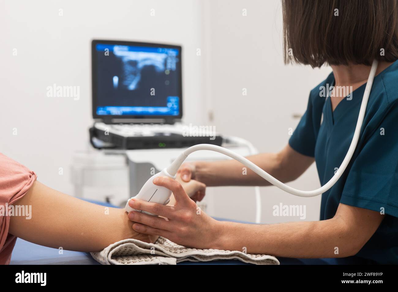 Professional healthcare worker performs an ultrasound scan on a patient ...