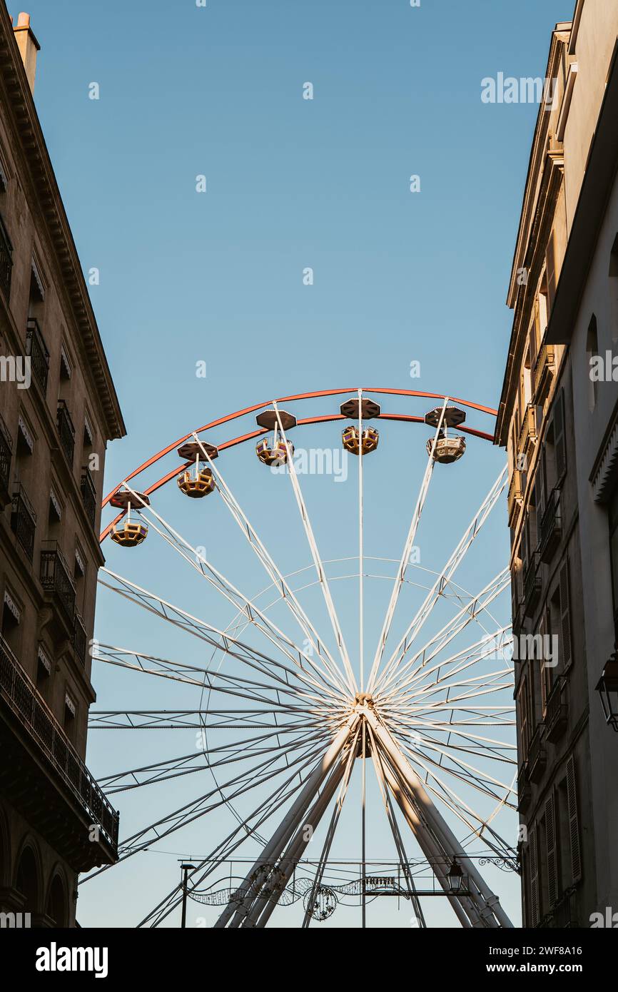 From below Ferris wheel rises majestically between buildings ...