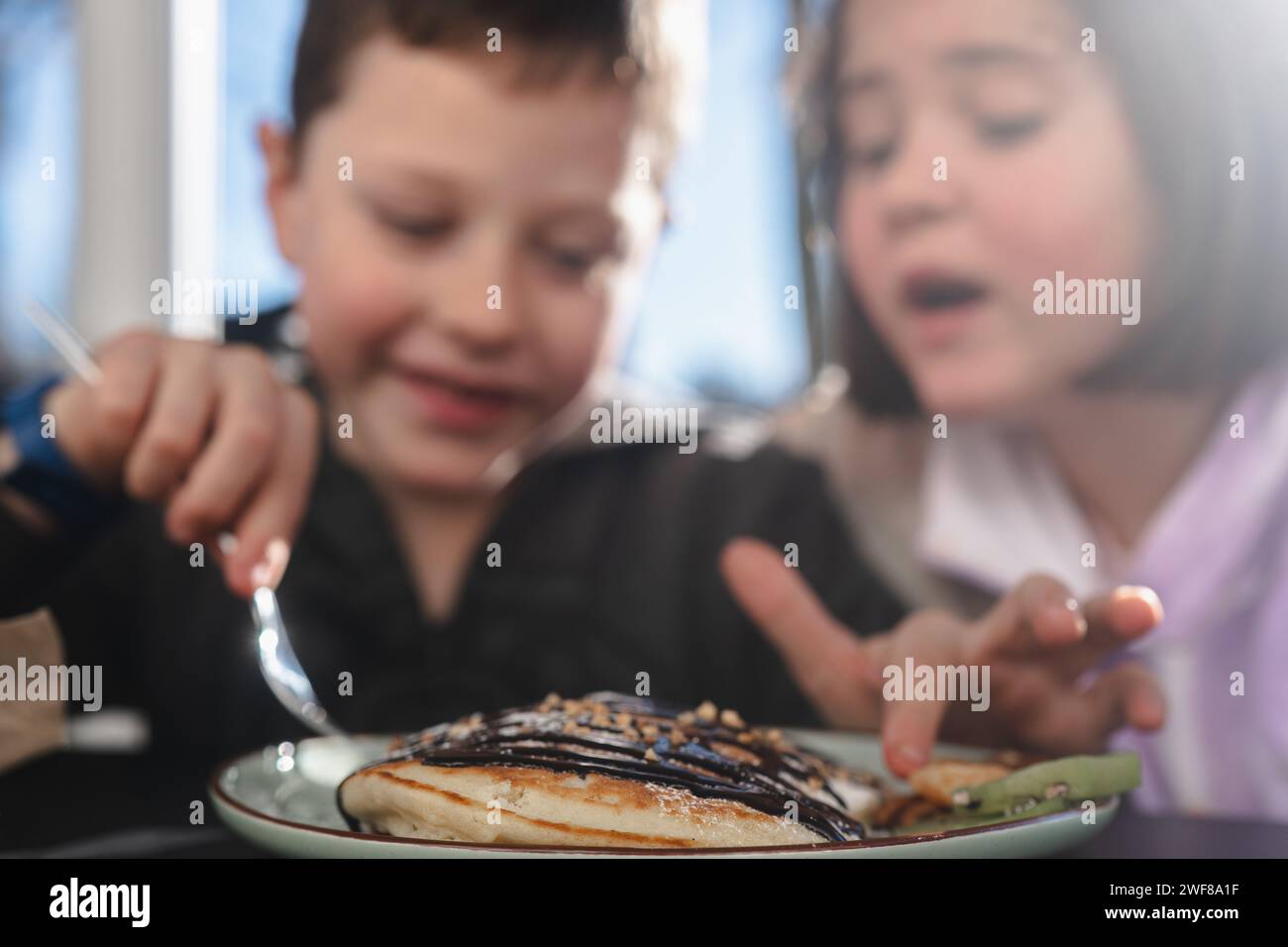 Two children enjoying a meal together, with a boy holding a fork over a ...