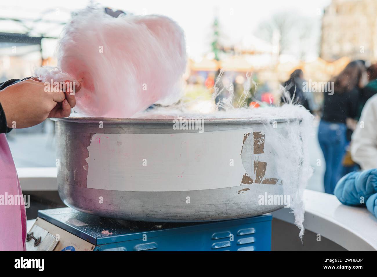 A cropped unrecognizable person making a large fluffy cotton candy at a ...