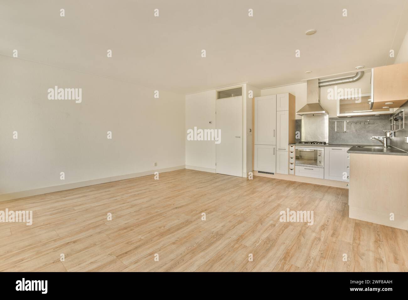 An empty, spacious apartment interior with a modern kitchen set and ...