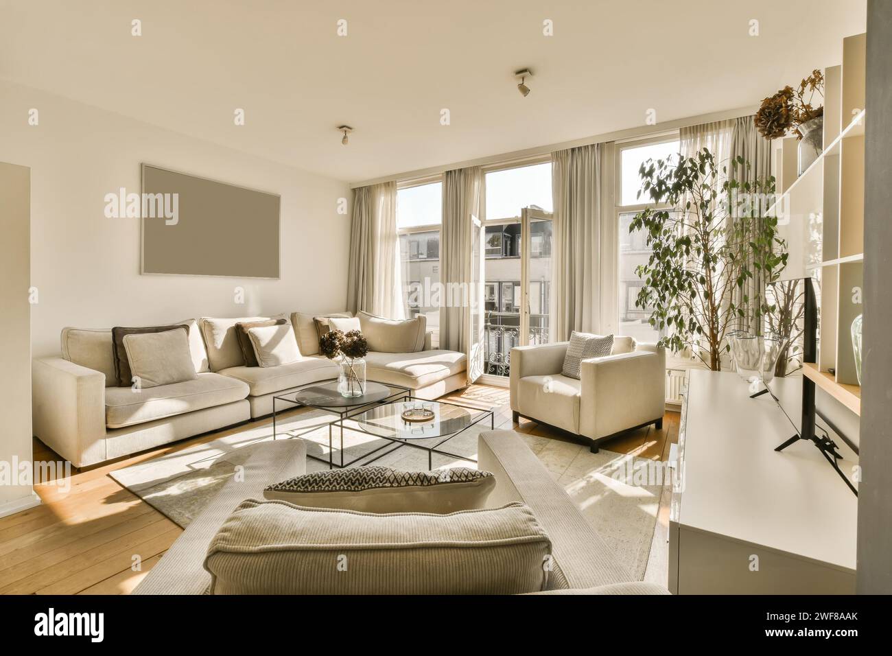 A spacious sunlit living room featuring a comfortable beige sofa ...