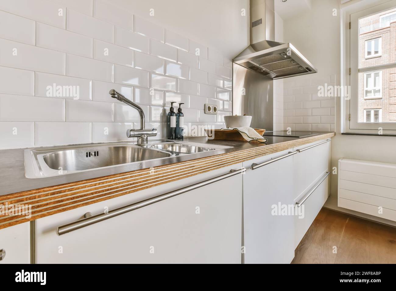 A contemporary kitchen featuring stainless steel sink, white subway ...