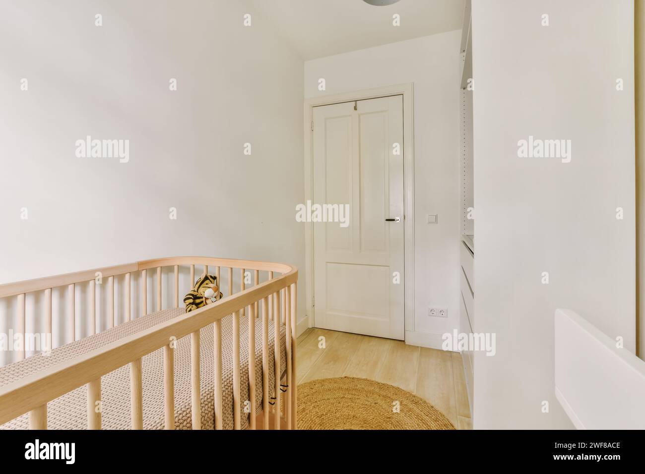 A contemporary nursery features a wooden crib beside an airy window ...