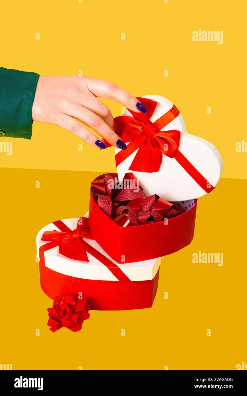 Anonymous hand opening a heart-shaped gift box with red ribbons on a ...
