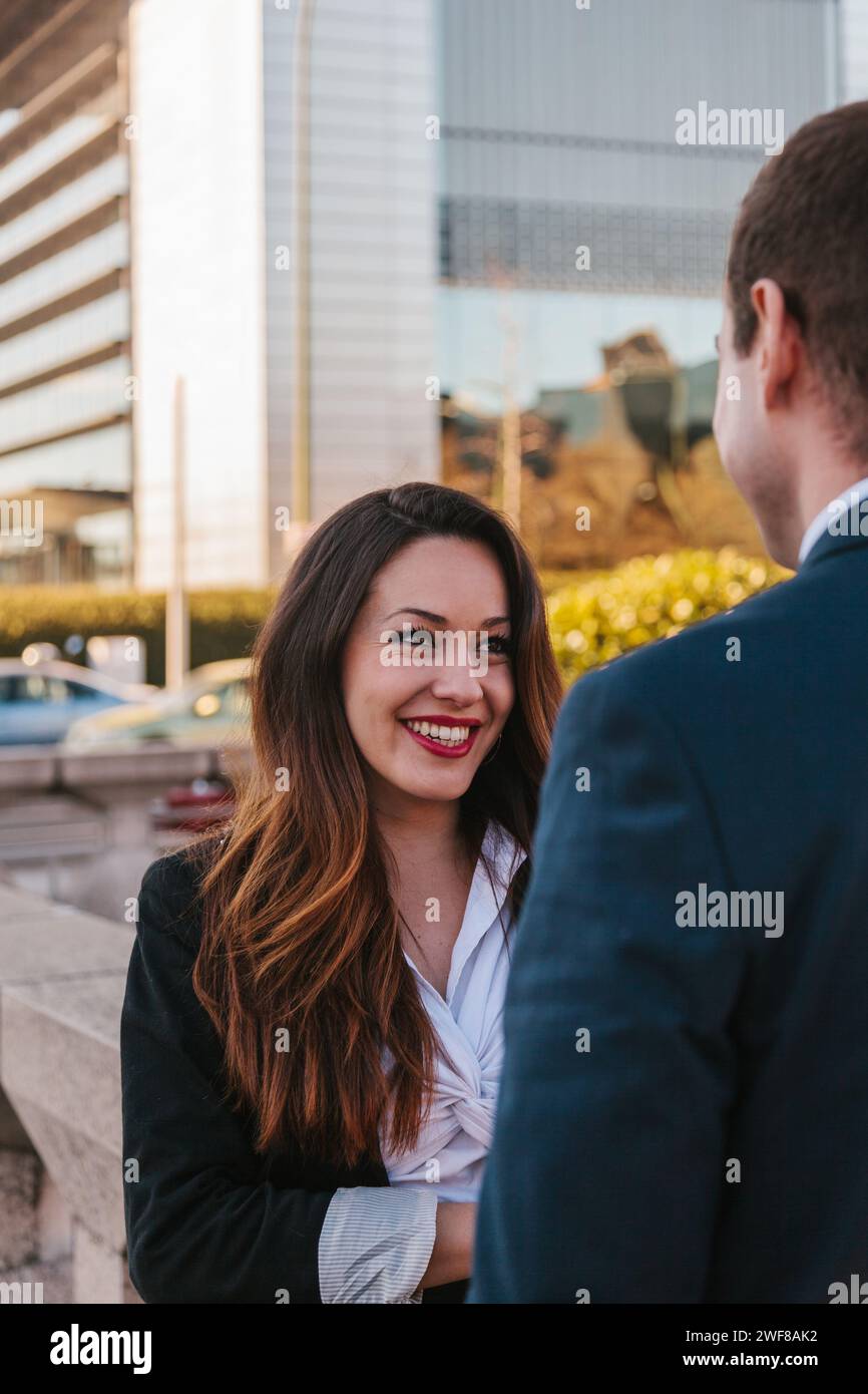 A professional woman smiles engagingly at a colleague against the ...