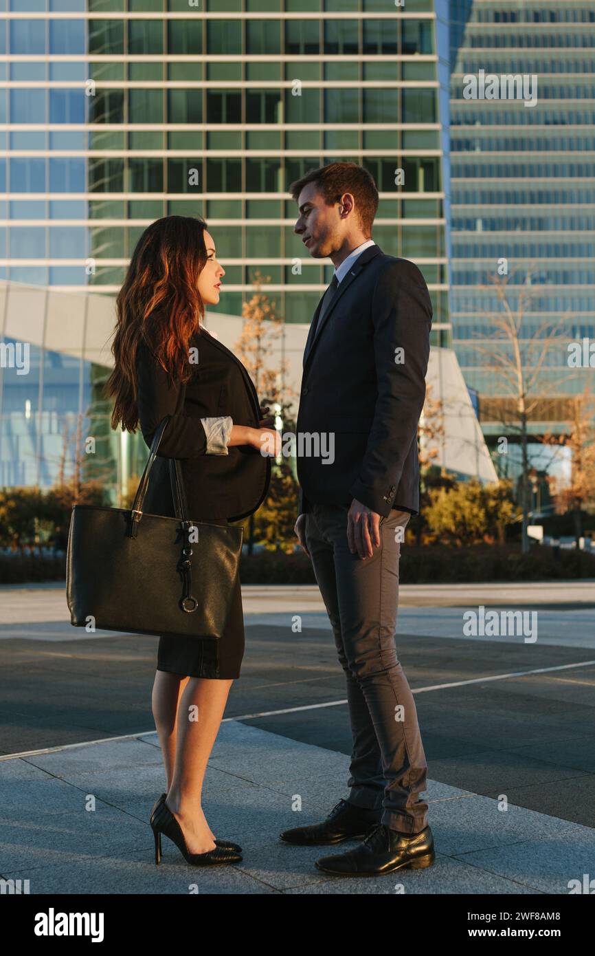 Two professionals in formal attire engaging in a conversation with ...