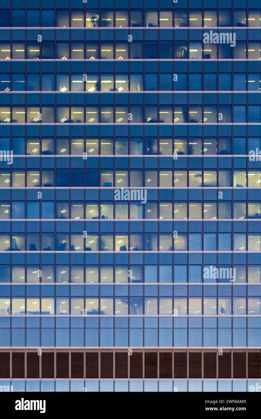 Evening illuminates the interior of an office building, showcasing rows ...