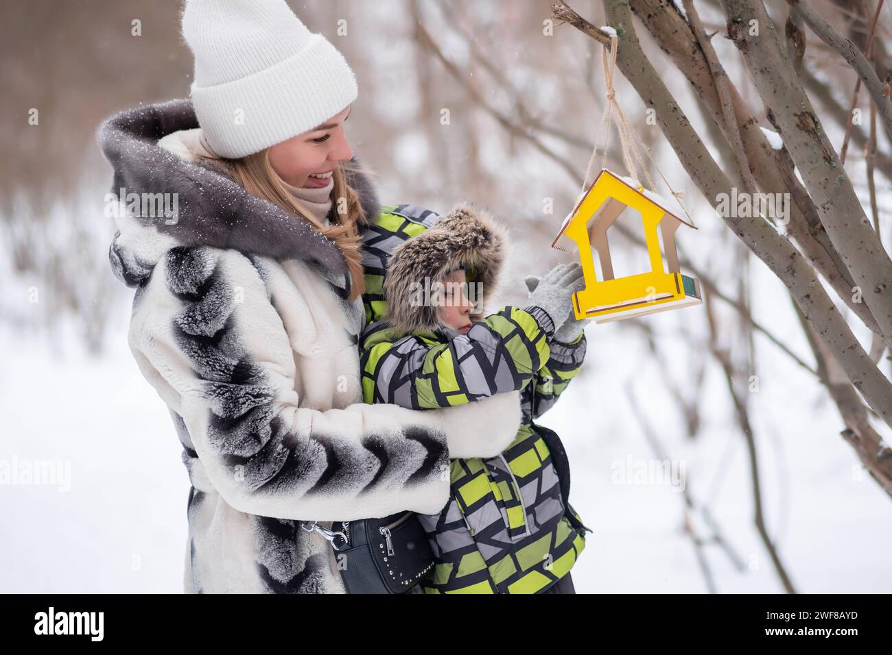 mother and son in a winter park feed birds using a feeder Stock Photo ...