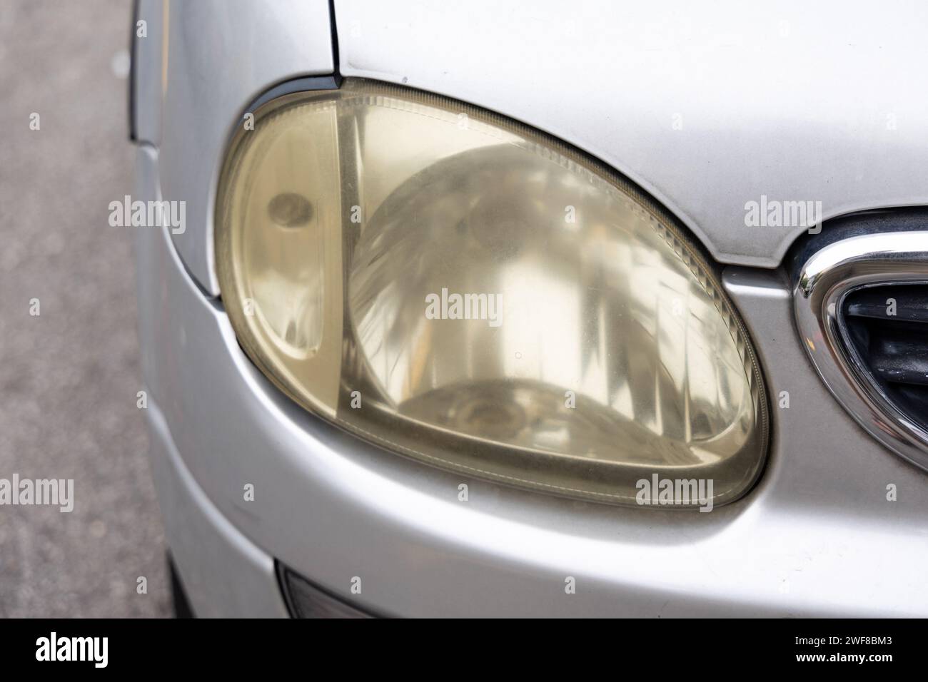 Hazy opaque yellowed front head lamp of car reduces light pass-through ...