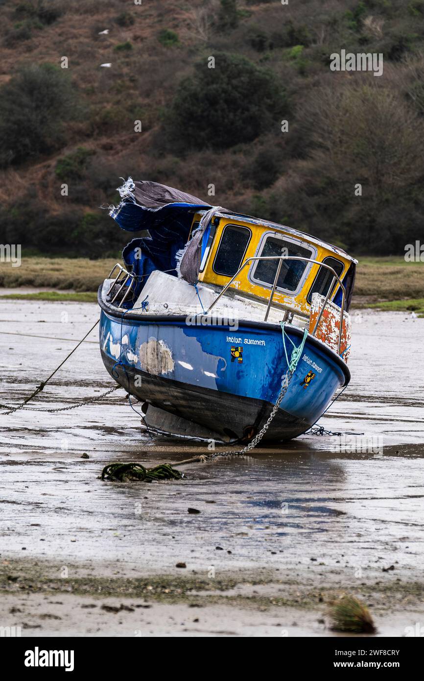 A boat being restored moored at low tide on the tidal Gannel Estuary in ...