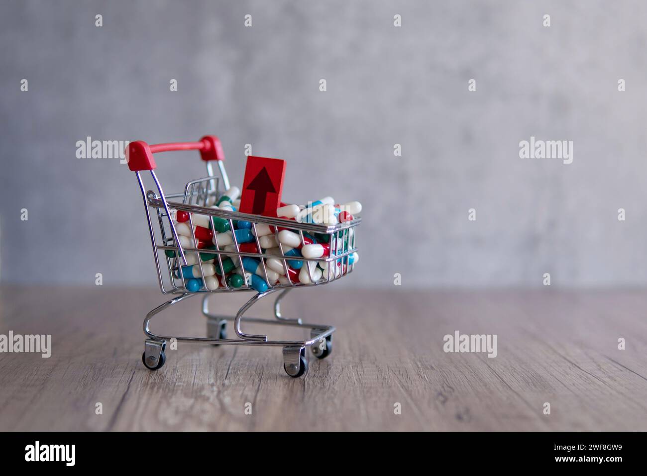 A shopping cart overflowing with colorful pills with a red arrow ...