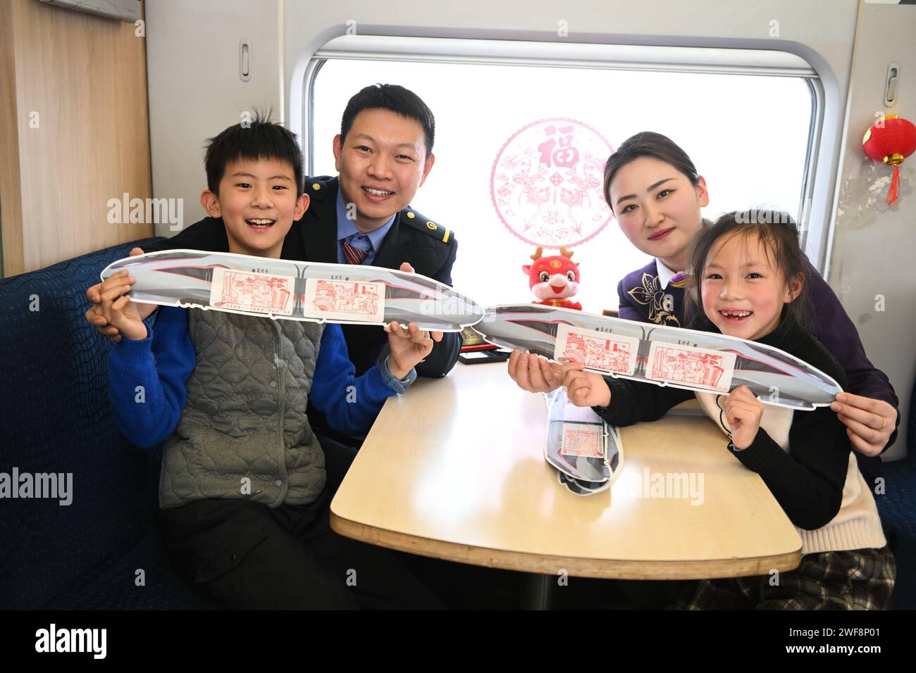 Nanjing. 29th Jan, 2024. Staff members and young passengers show ...