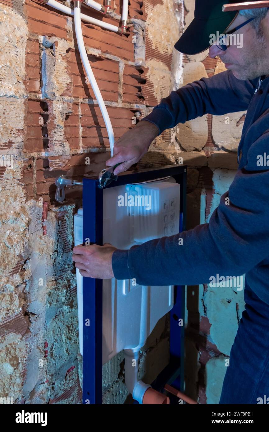Professional plumber installing the frame of a wall-mounted toilet on ...