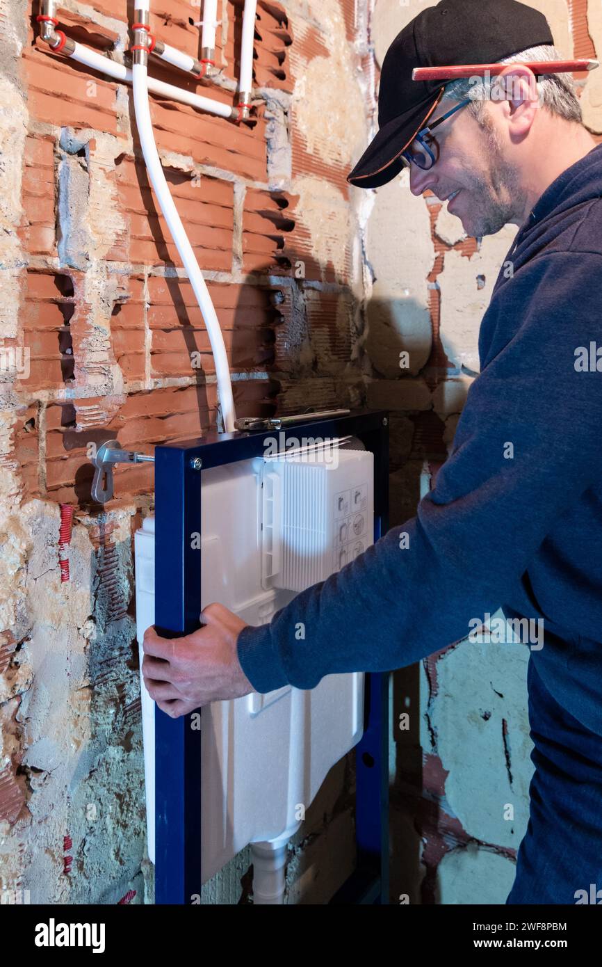Professional plumber adjusting the installation of a wall-mounted ...