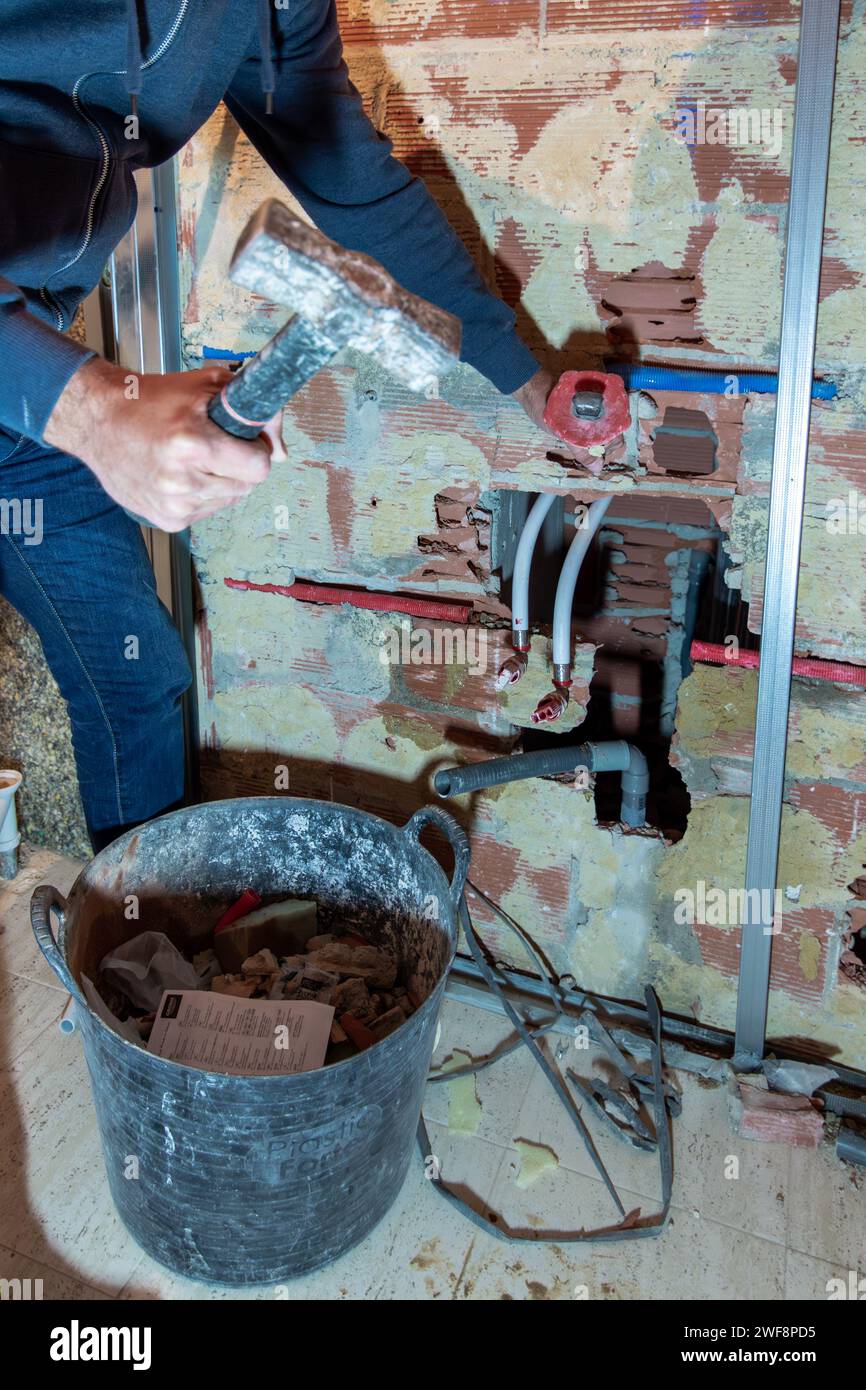 Bricklayer chipping a brick wall at a construction site to make way for ...