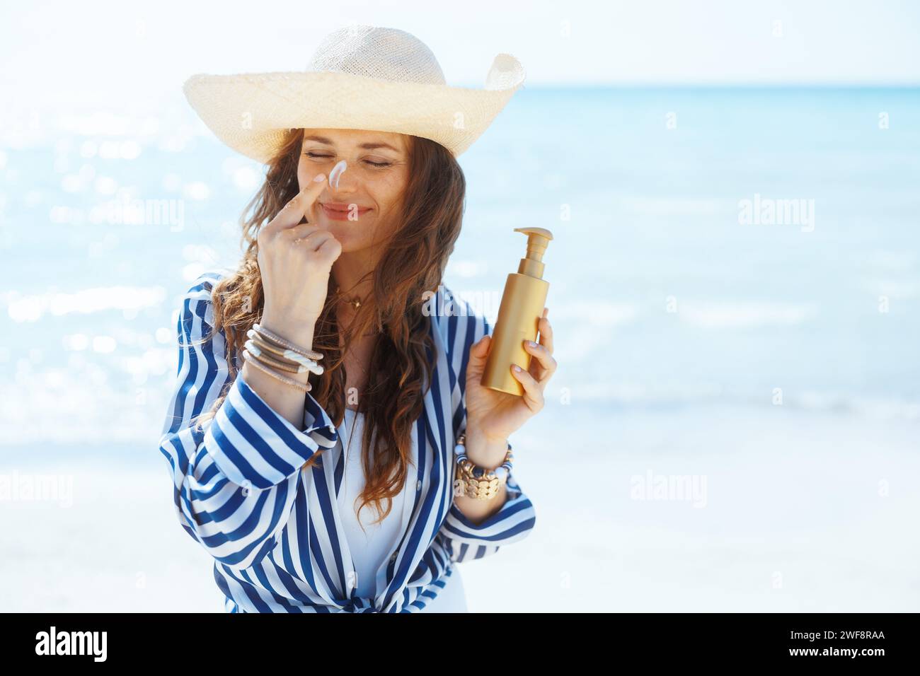 smiling modern female on the beach with spf Stock Photo - Alamy
