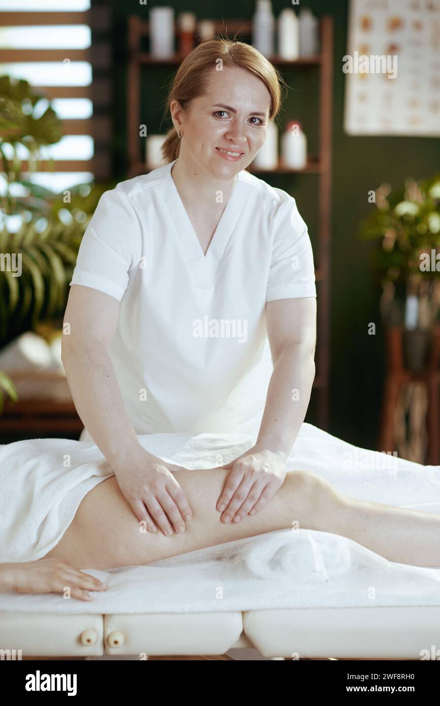 Healthcare time. massage therapist in massage cabinet massaging clients leg on massage table ...
