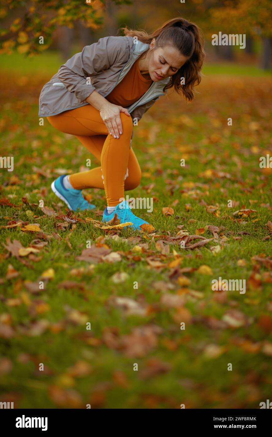 Hello autumn. sad modern woman in fitness clothes in the park got a leg ...