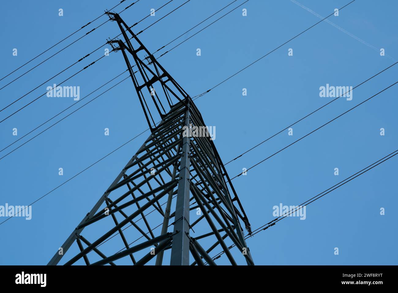 Powerline lattice mast and high voltage power lines against blue sky ...