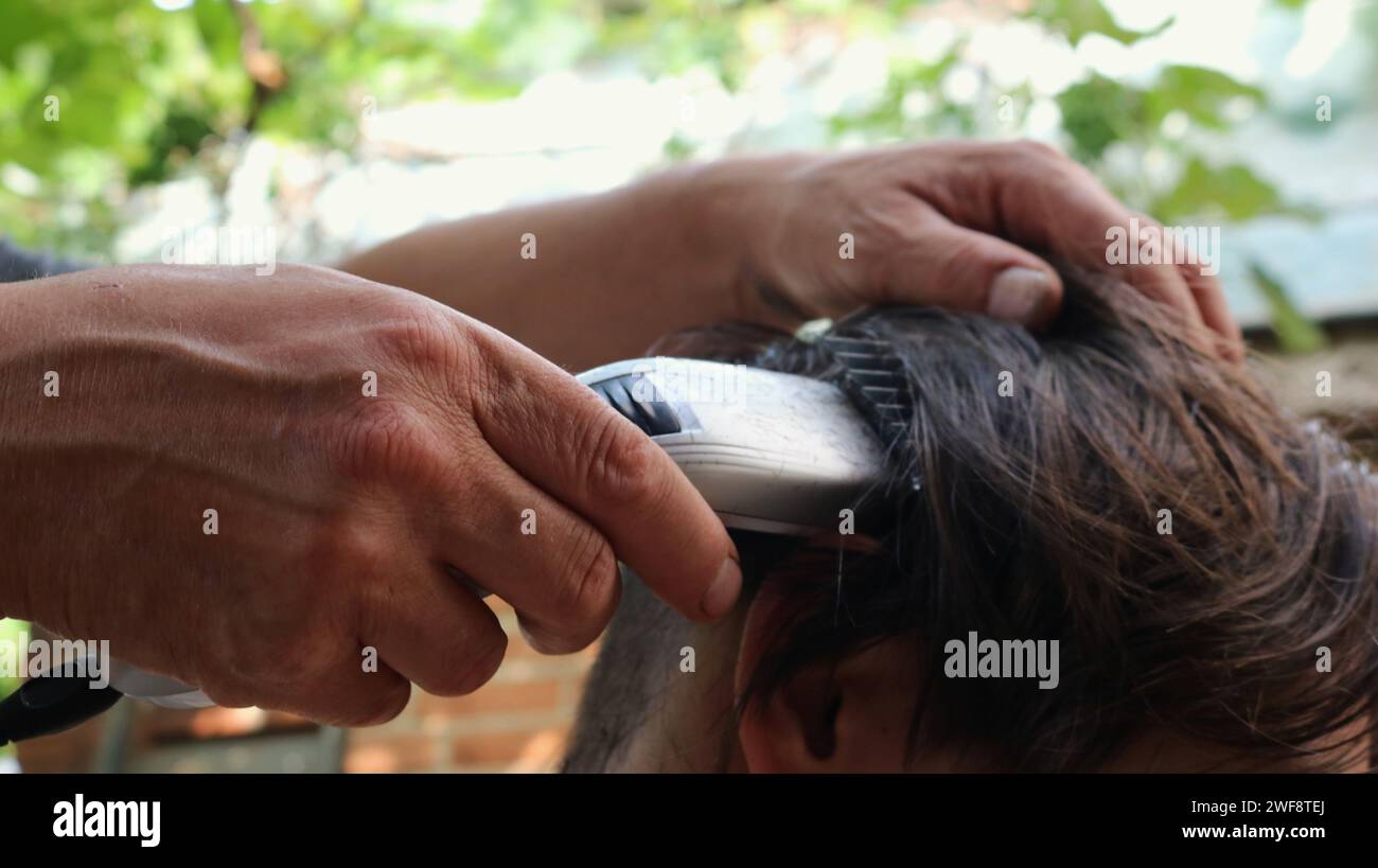 hands of a hairdresser cutting the back of a person's head with a ...
