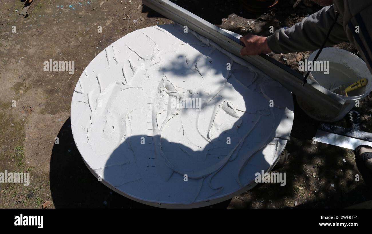 the master applies a thick layer of elastic white mastic to the round ...