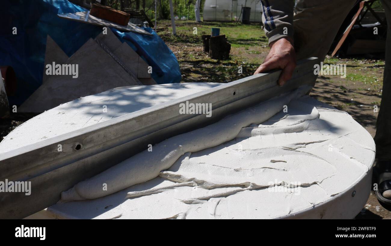 applying and leveling a layer of soft finishing mortar on a flat round ...