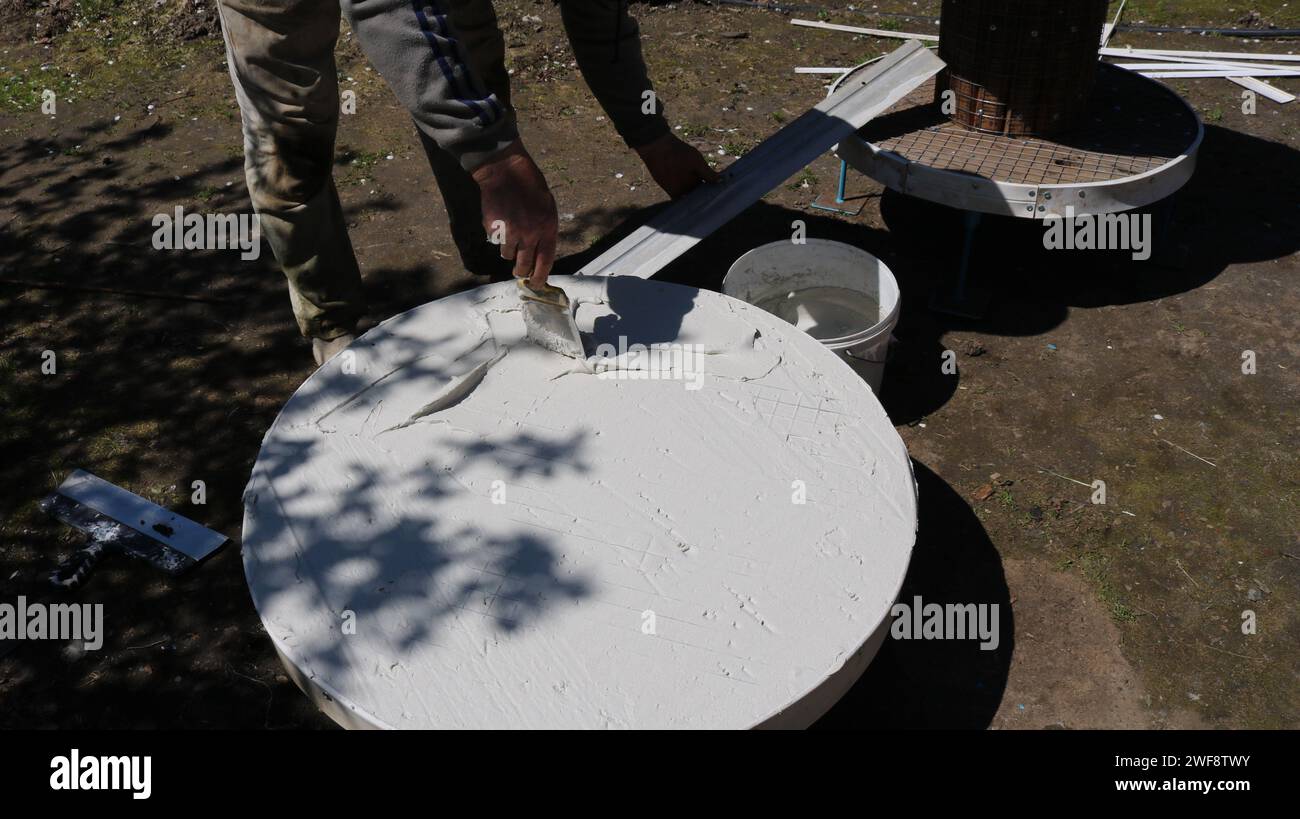 covering a round tabletop with plaster in the process of making ...